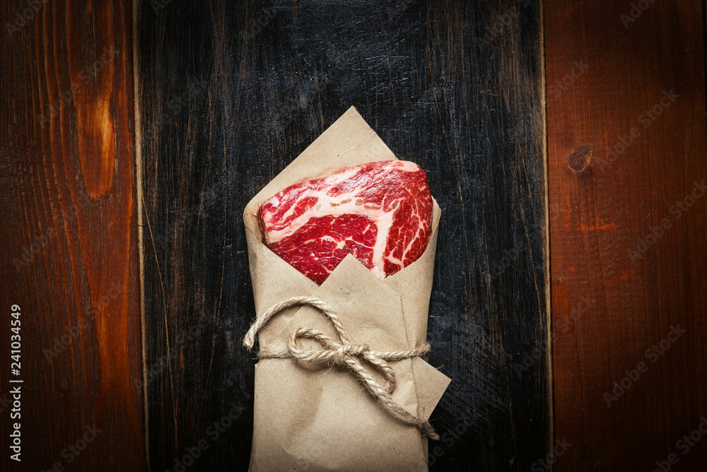 meat from a butcher shop wrapped in paper. A piece of marbled beef in ...