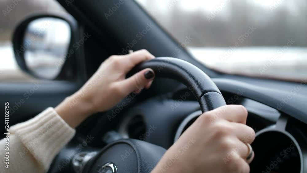 Closeup of female hands. The girl drives a car, turns the steering ...