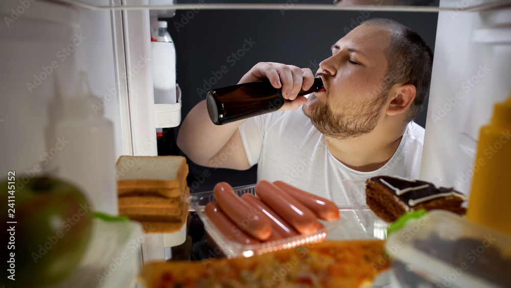 Fat man drinking beer with pleasure from fridge at night, unhealthy ...