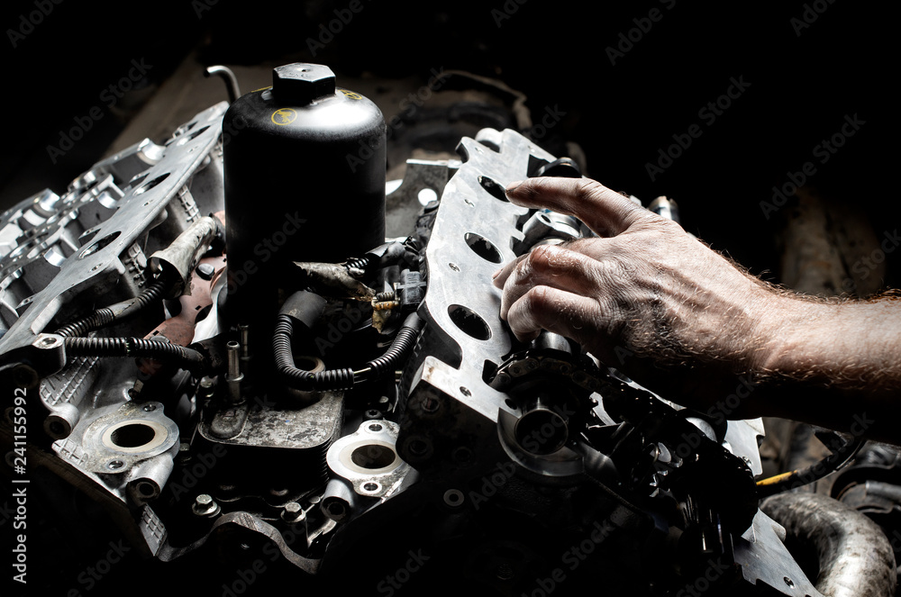 Mechanic hand checking and fixing a broken car in car service garage ...