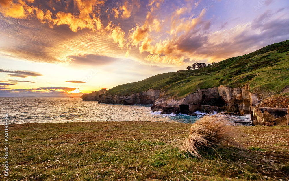 An epic sunset with dramatic burning clouds in Tunnel Beach of Dunedin ...