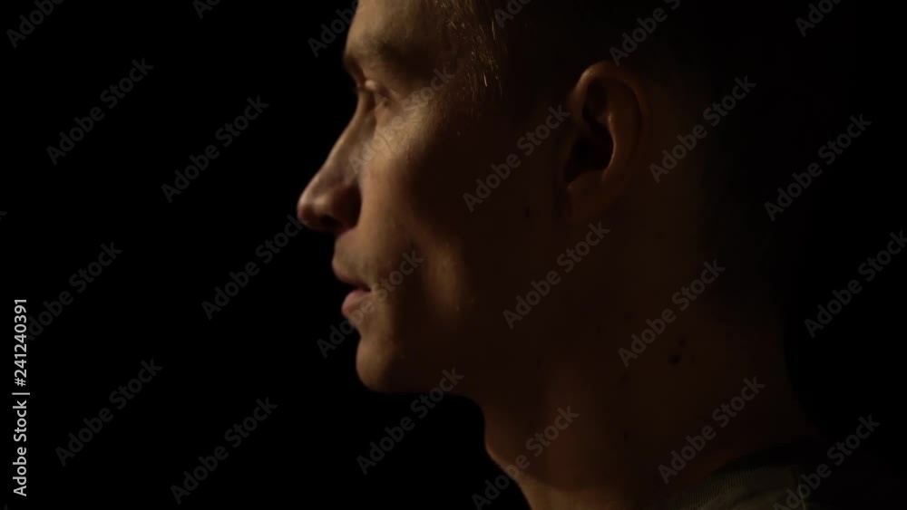 Young man falls light on the face in dark. The profile of a man in the ...