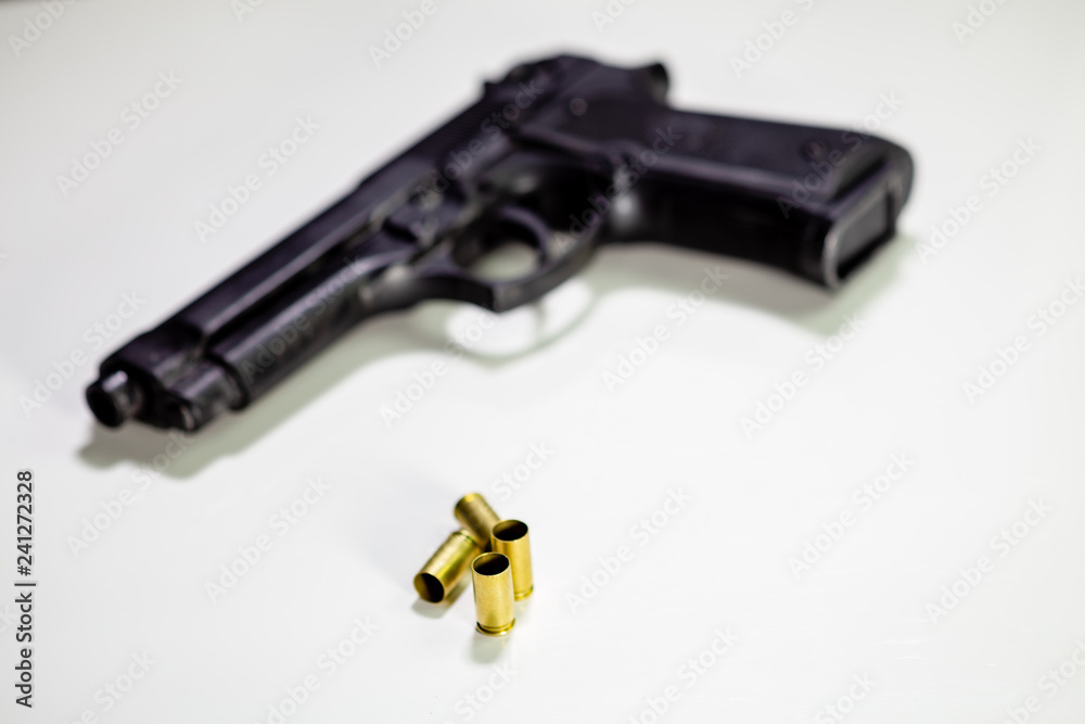 Handgun with 9mm shell casings on white table Stock Photo | Adobe Stock
