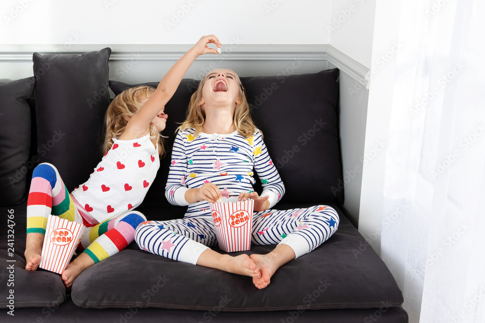 Little girl feeding popcorn to her sister Stock Photo | Adobe Stock