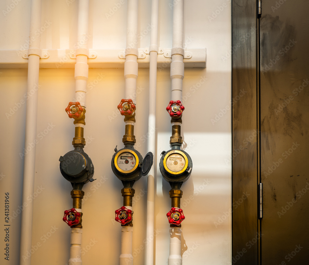 Single water meter and red valves on white concrete wall of house ...