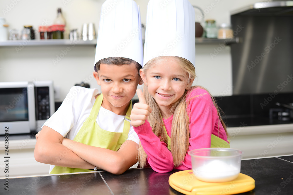 beautiful young happy kids boy and girl cooking and baking a cake in ...