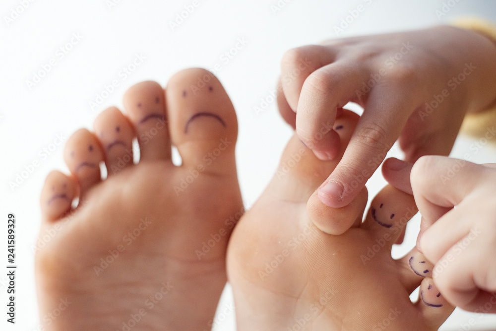 Female toes with painted smileys and children's hands. Foot care ...