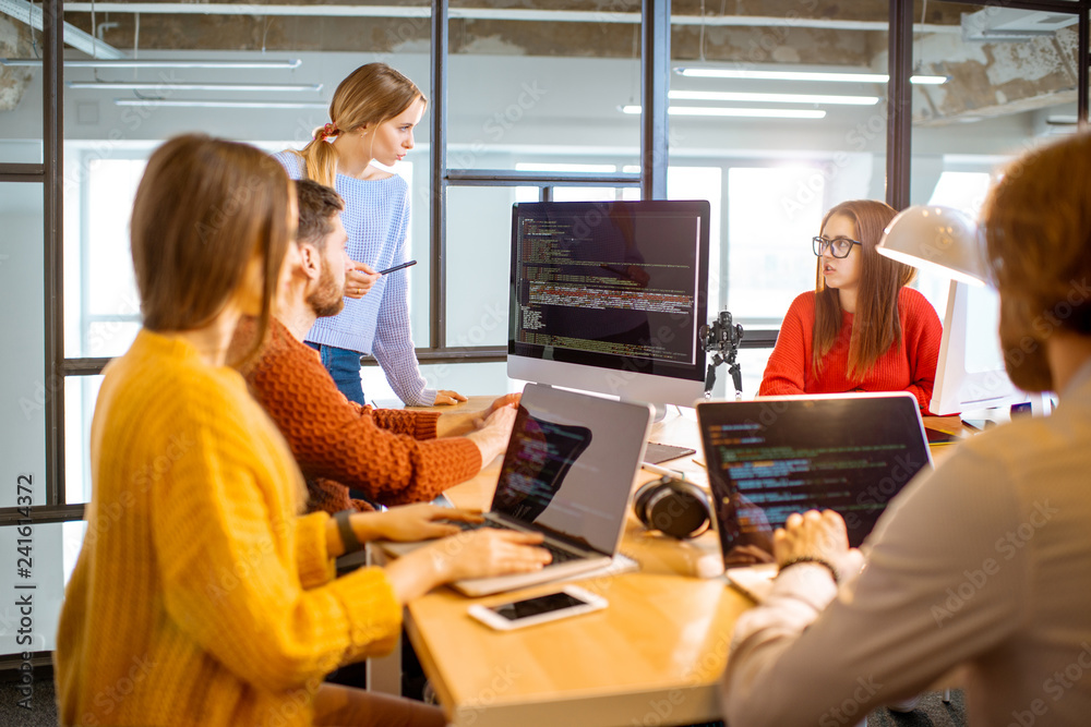 Team of a young programmers dressed casually working on computer code ...