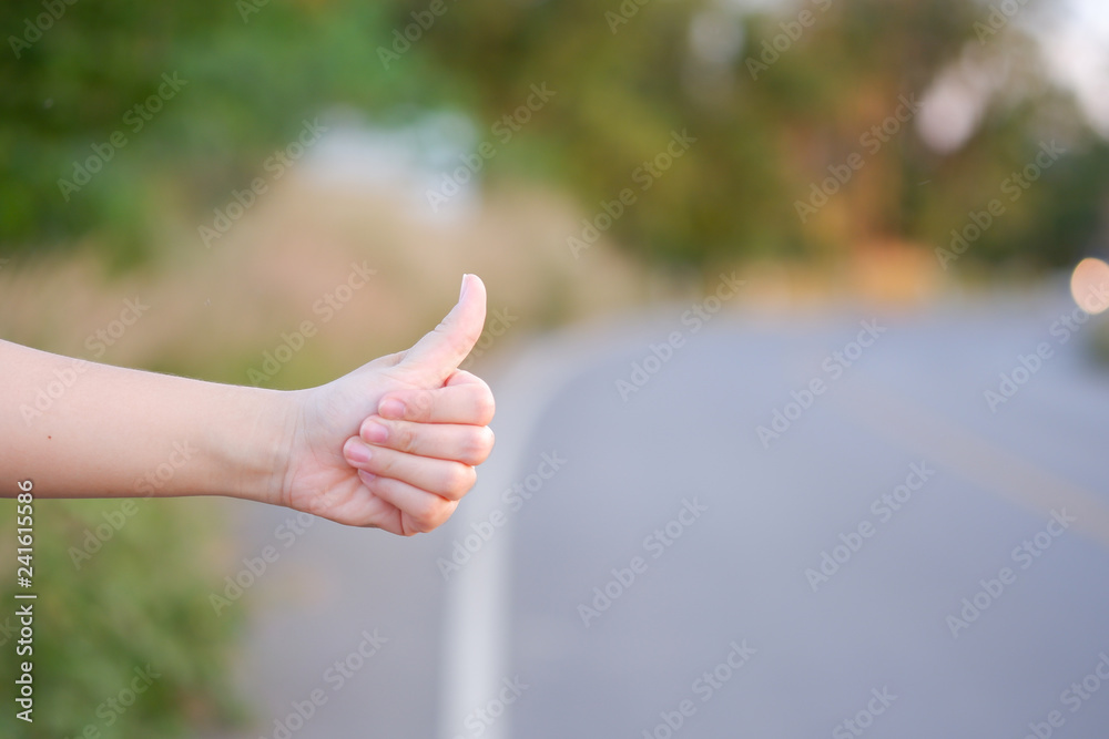 Foto de Female traveler hitchhiker holding hand gesture to stop a car ...