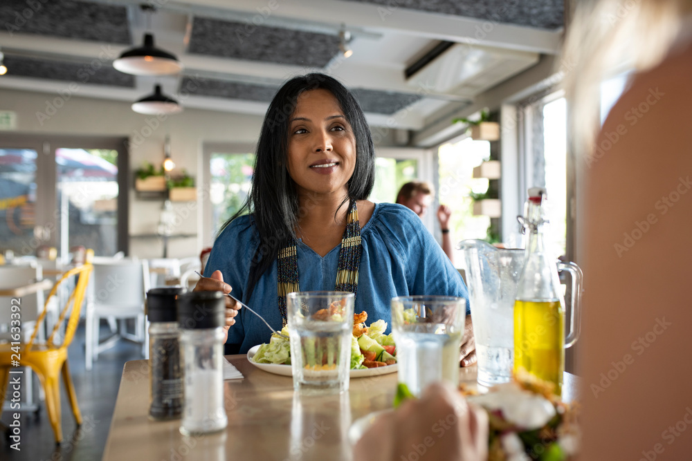 Female friends talking while eating food in restaurant Stock Photo ...