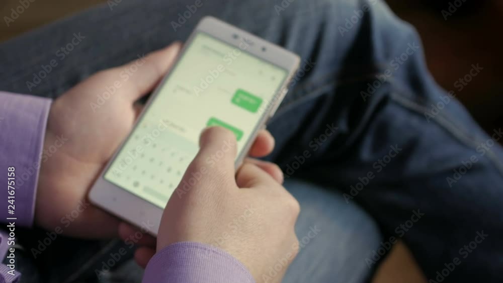 A man writes a texting SMS message using a smartphone. Male texting ...