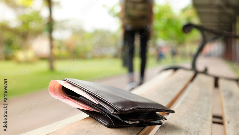 Leather purse with a money lying on the park bench while tourists are ...