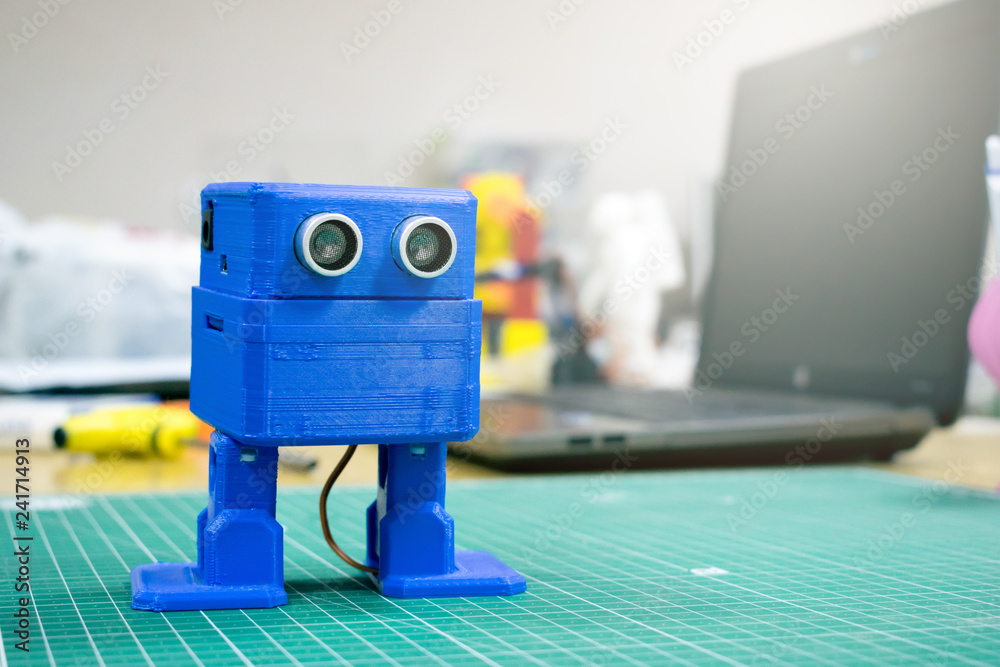 3D printed Funny dancing blue robot on the background of devices and ...