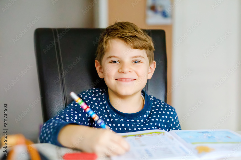 Happy smiling little kid boy in pajamas at home making homework at the ...