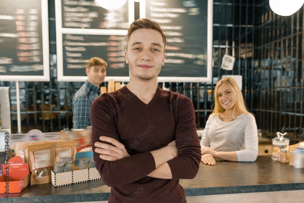 Young team of three cafe workers, people posing and smiling at coffee ...