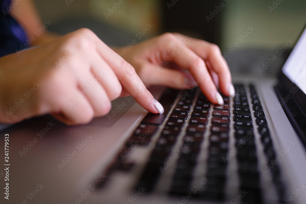 Close-up of woman's hand using laptop with blank screen on bed in home ...