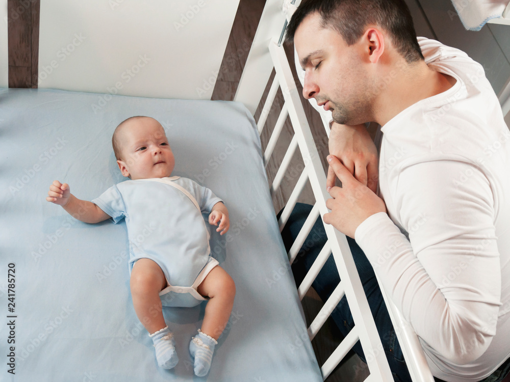 Young dad is tired of putting a small child to bed. Dad and son ...