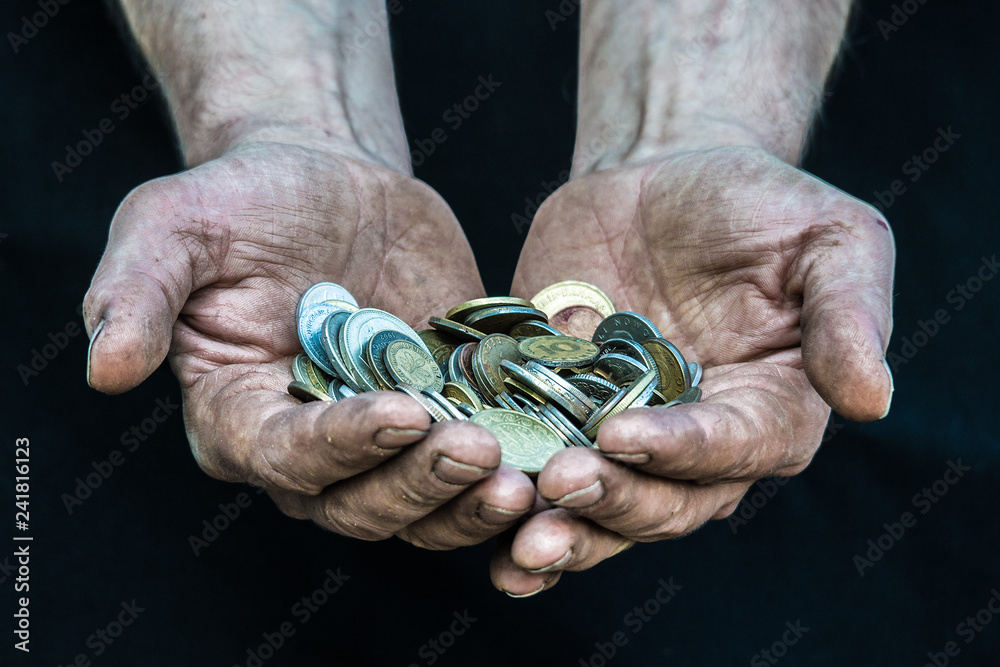 Dirty hands homeless poor man with many coins from different countries illustrating poverty in ...