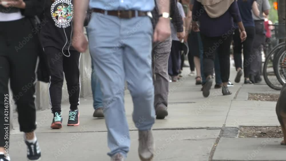 Pedestrians walking down a busy city street. Low angle shot of feet and ...