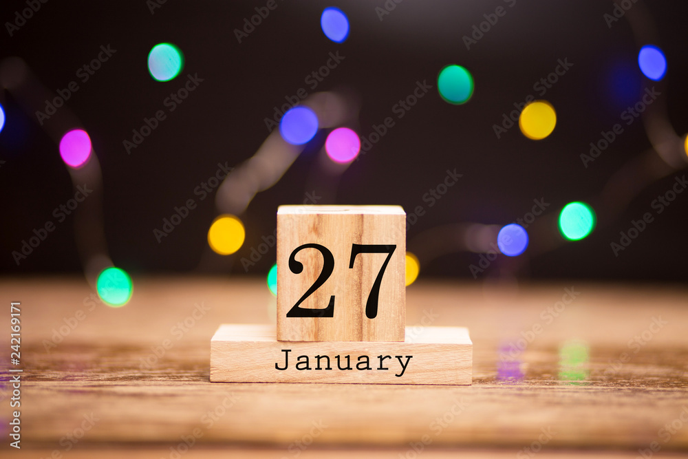 Wooden calendar with black 27 january word at center of dark background ...