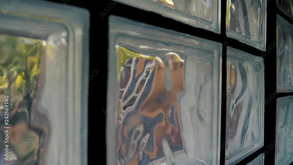 Trees and scenery outside viewed through glass block bends the shapes ...