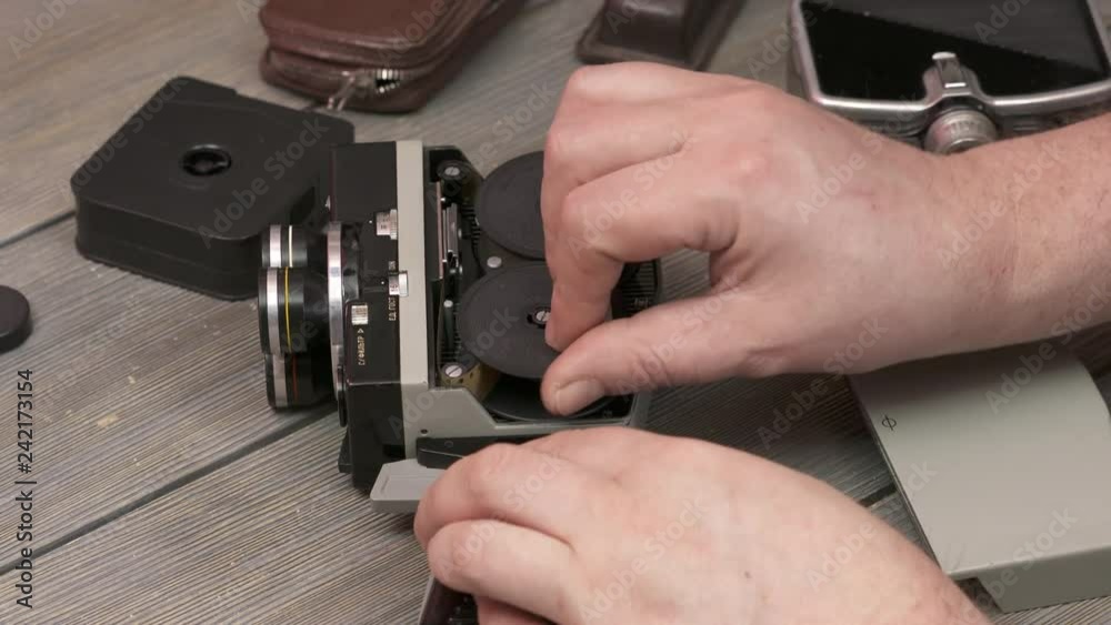 Man using vintage 8mm film movie camera. Loading spool of film into the ...