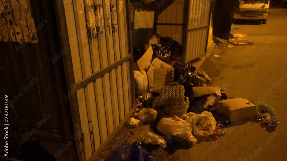 Garbage bins filled with trash on empty city street at night Stock ...