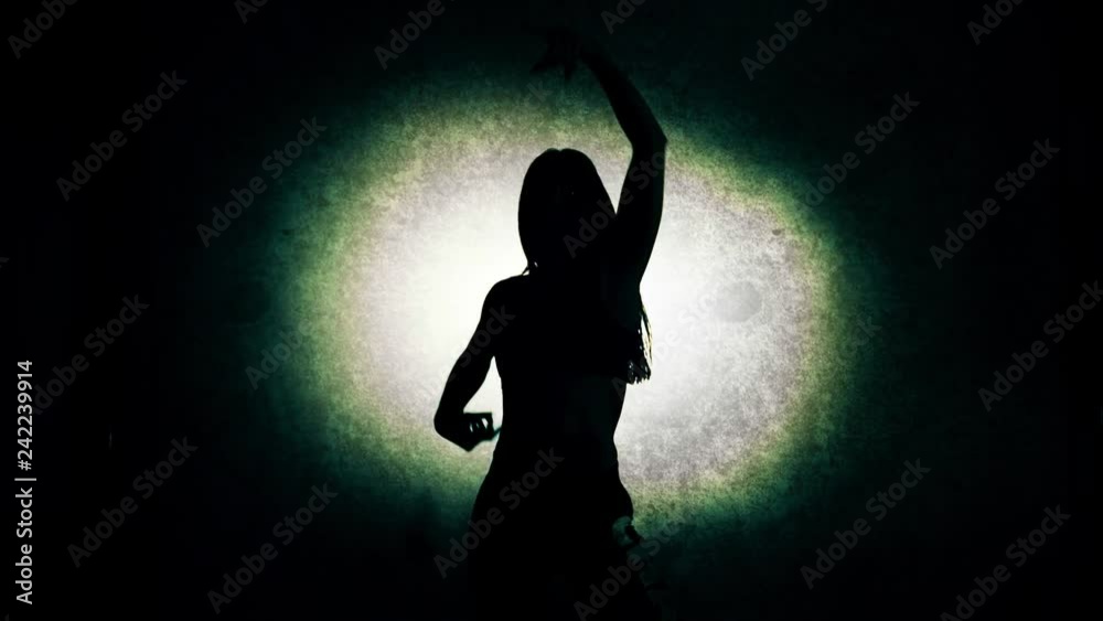 Female shadow dancer energetically dancing against a black background ...