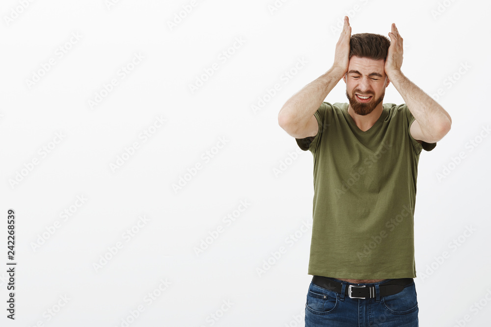 Portrait of man suffering huge headache or migraine grabbing head with ...