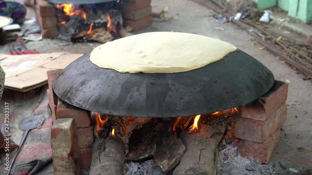 Indian woman cooking traditional indian bread, big chapati cooking on ...