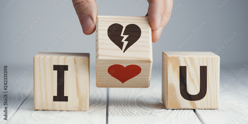 Hand flipping a wooden cube to remove the red heart for the broken ...