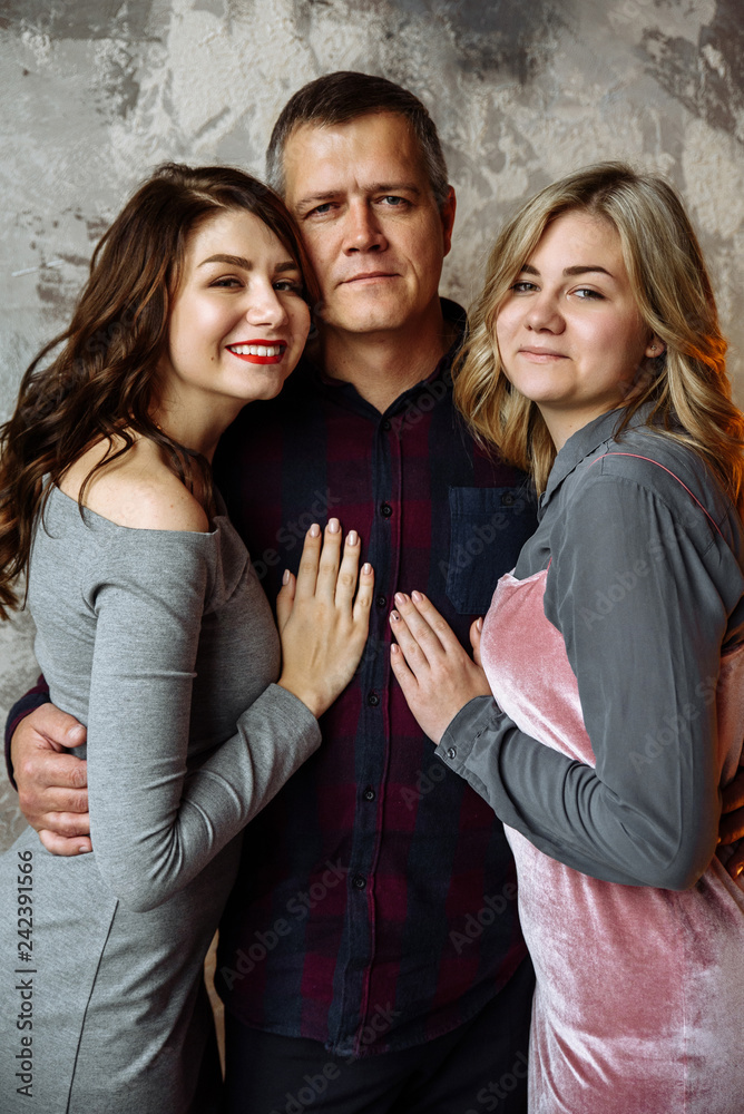Father and his adult daughters. Happiness. Two daughters hugs their ...