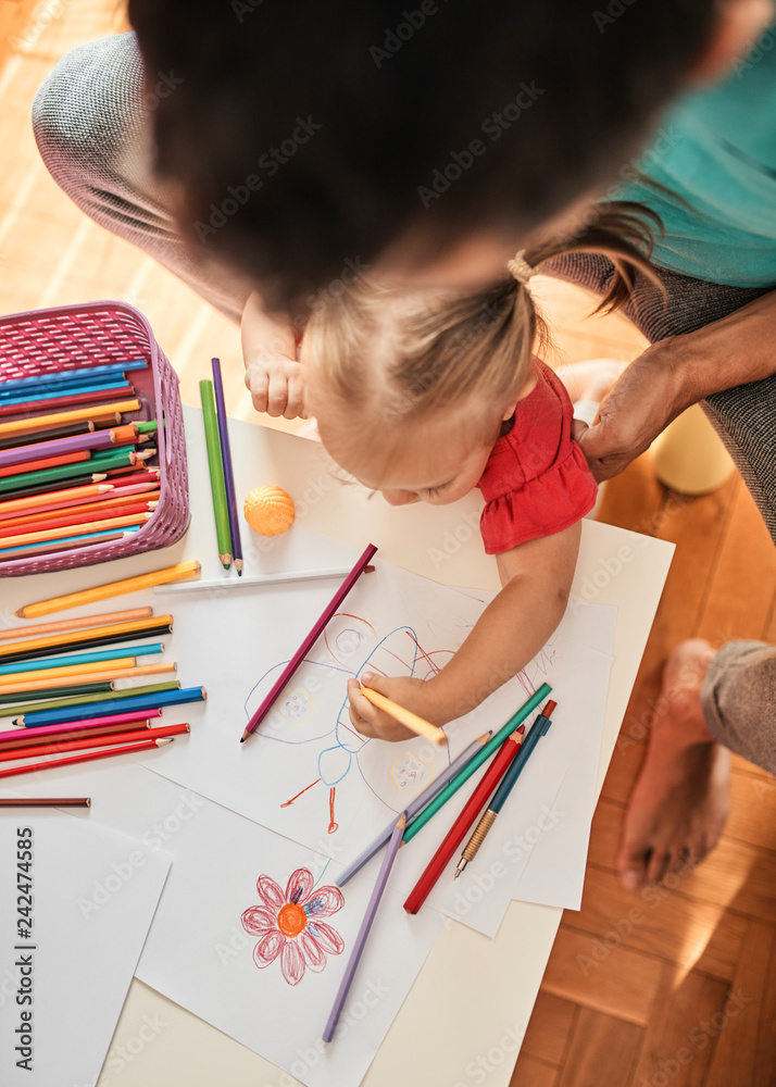 Little girl drawing with colored pencil while her father watching her ...
