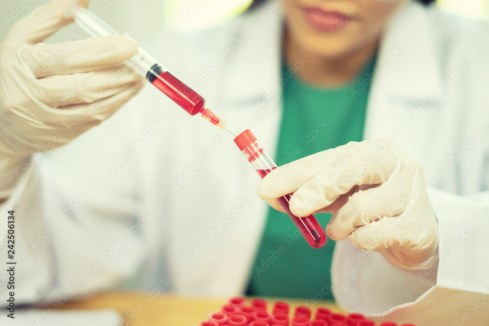hand of a lab technician or medical doctor holding syringe drops of ...