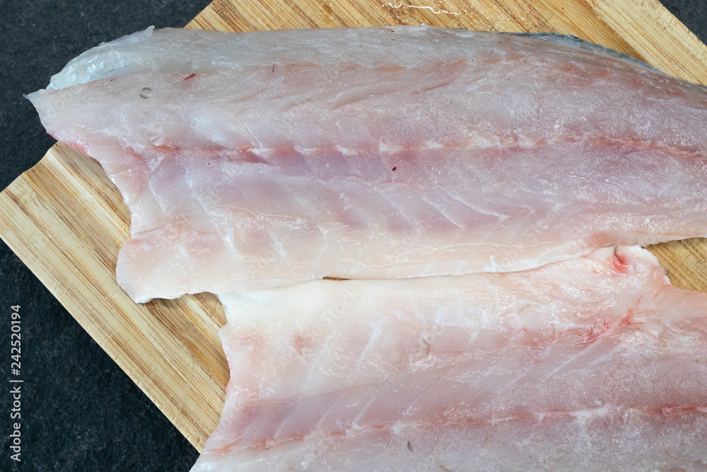 fillet of filleted sea bass on a wooden table and a slab of black ...