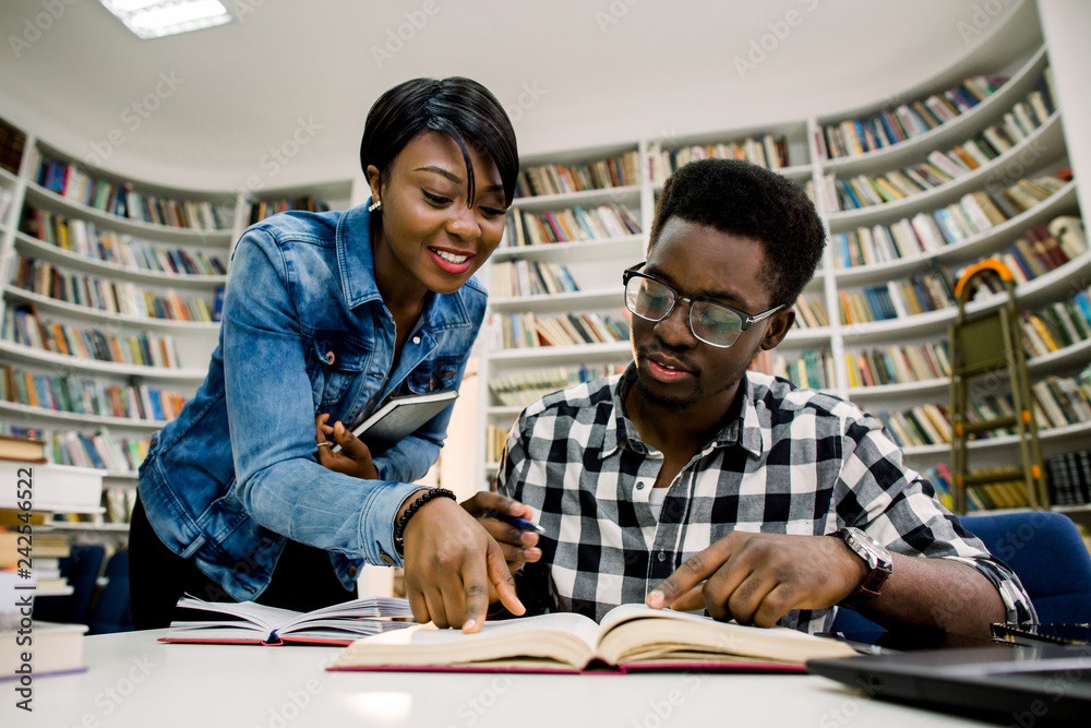 University students african boy and girl sitting together at table with ...