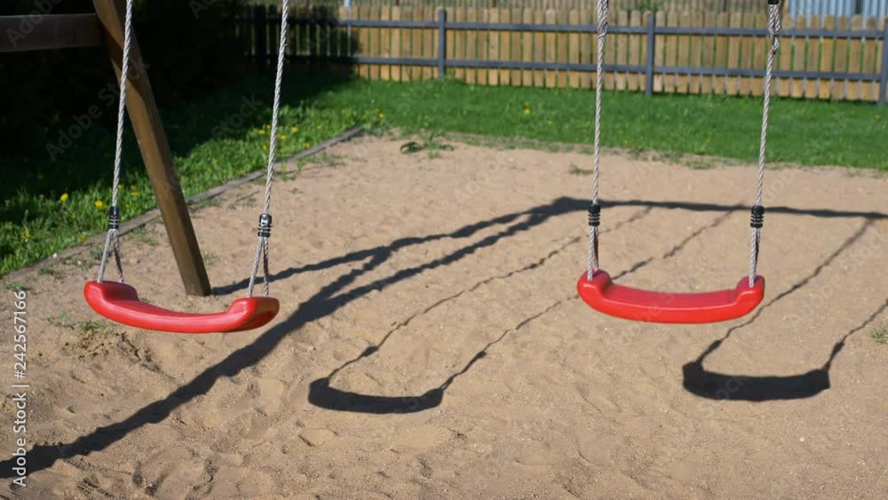 Children’s swings moving back and forth in a children’s playground Two ...