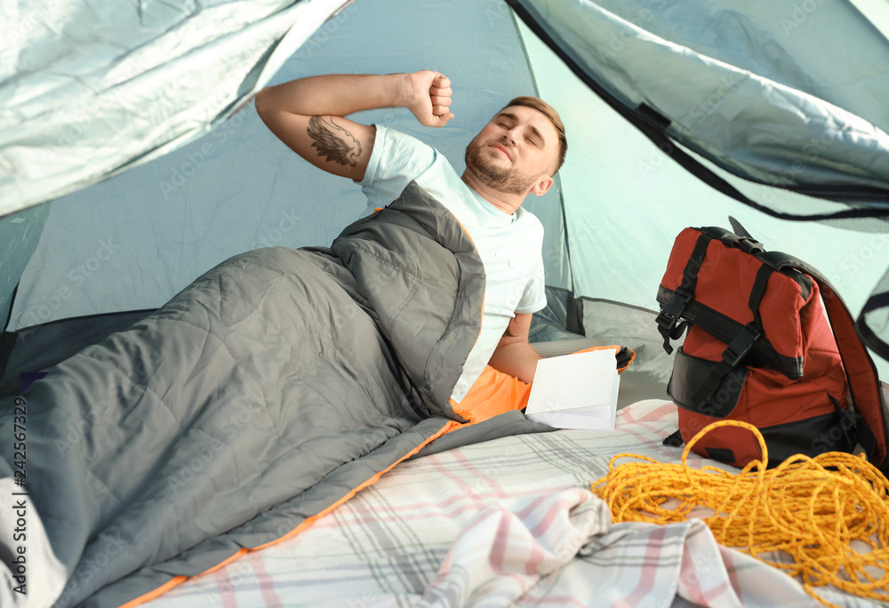 Young man stretching in sleeping bag inside of camping tent Stock Photo ...