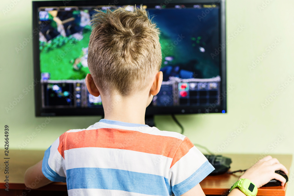 cute boy playing computer game behind the monitor Stock Photo | Adobe Stock