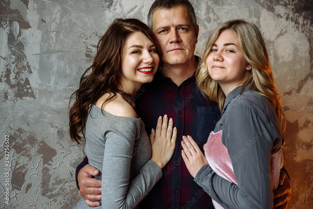 Father and his young daughters. Happiness. Two daughters hugs their ...