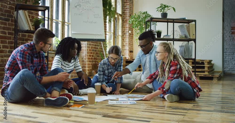 Group of the mixed-races students creating a studing project while ...