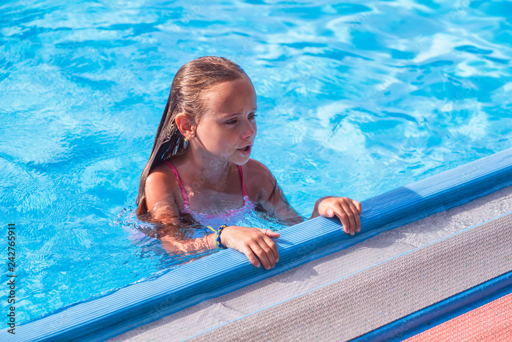 Beautiful little girl swims in the pool , cute little girl in pool in sunny day.little girl ...
