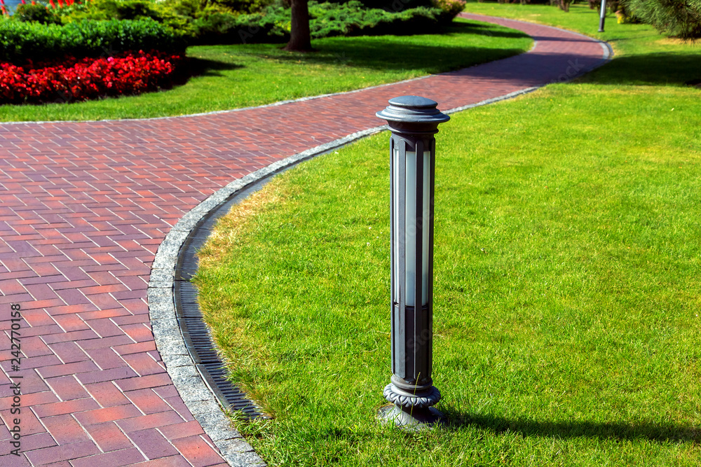 a pedestrian pavement with red tiles stretches along a curved path ...