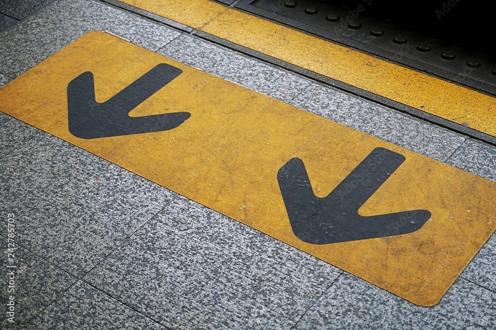 Arrow sign and yellow line on the floor. The symbol at the train ...