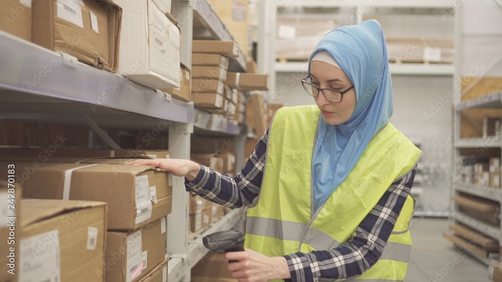 Muslim in hijab store worker conducts accounting using barcode scanner Stock Photo | Adobe Stock
