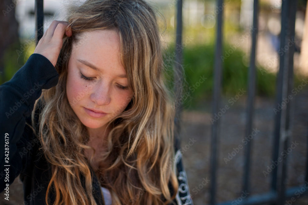 Young girl looking down and pulling hair behind her ear. Stock Photo ...