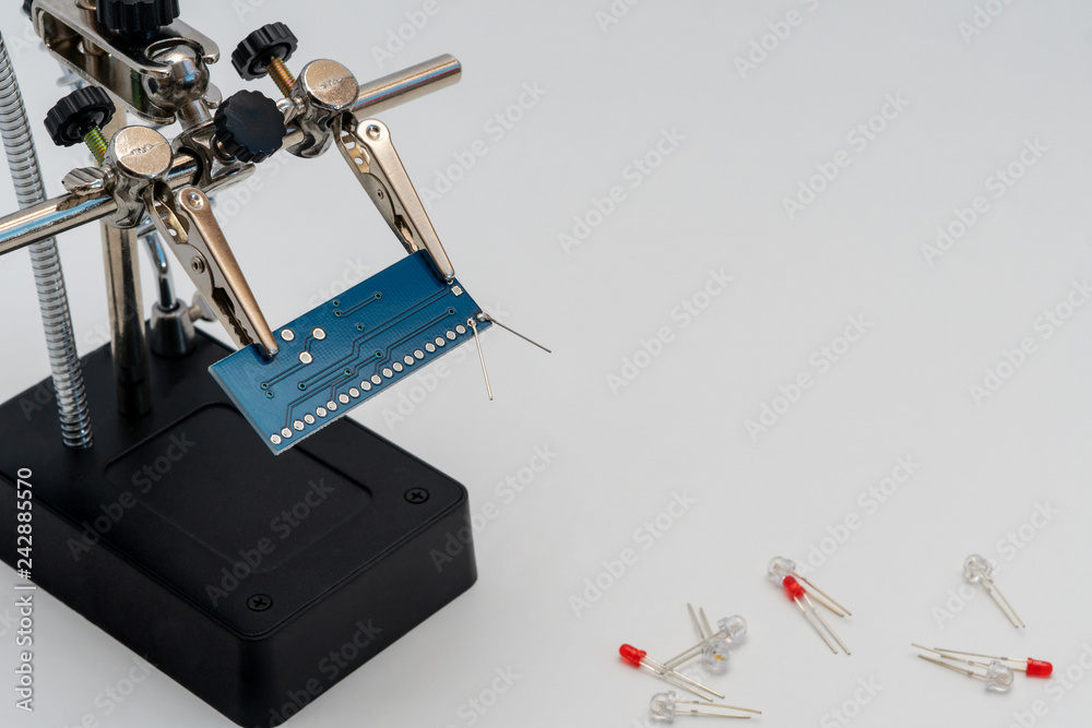 Blue circuit board in soldering helping hands (third hand or auxiliary ...