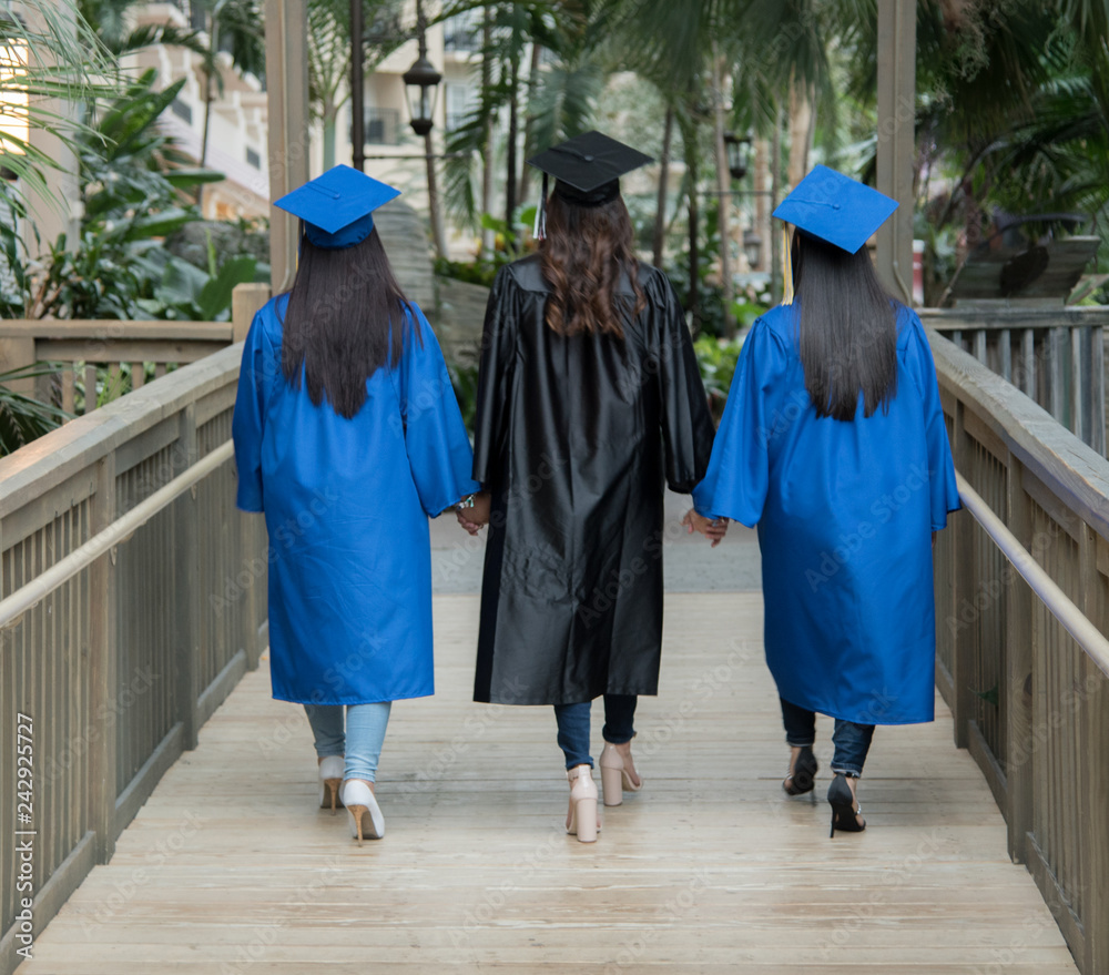 Three friends walking in graduation cap and gown Stock Photo | Adobe Stock