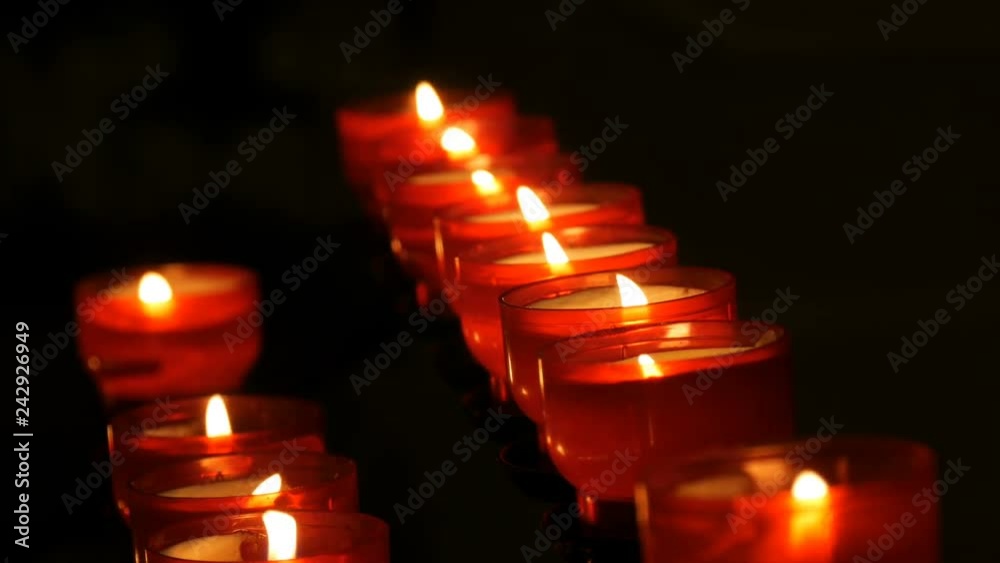 Row of christian prayer red round votive candles burn in the dark ...