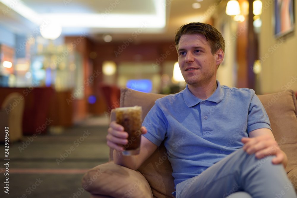 Young handsome man sitting and relaxing at the hotel lobby Stock Photo ...